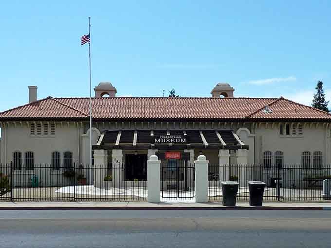 The Porterville Museum building stands dignified behind its iron fence, preserving local history in classic Mission Revival style.