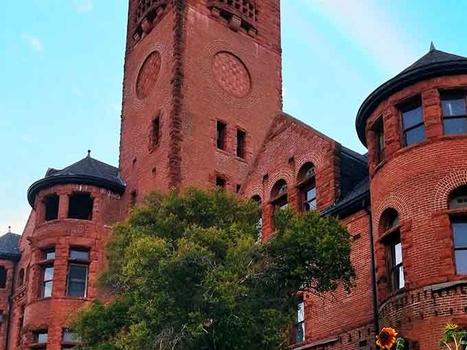 Red brick towers and turrets rising dramatically showcase Romanesque Revival architecture that commands attention and respect from every angle.