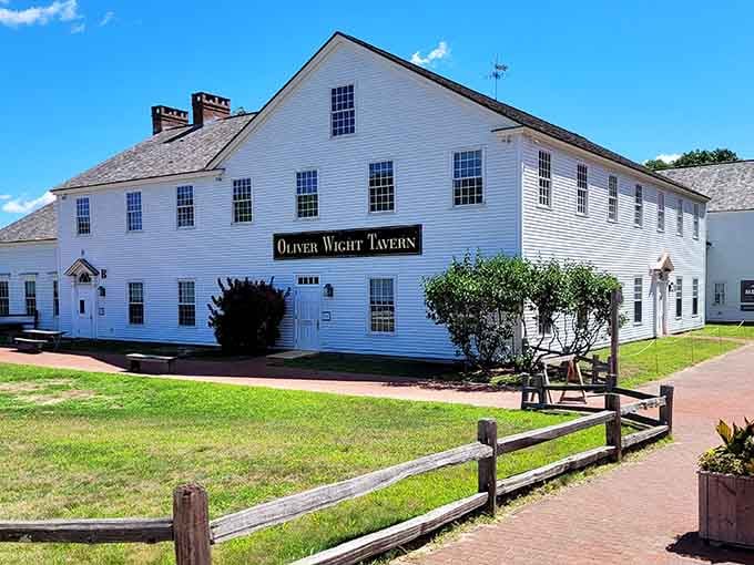 The Oliver Wight Tavern stretches long and white against the green lawn, looking exactly like colonial hospitality should look.