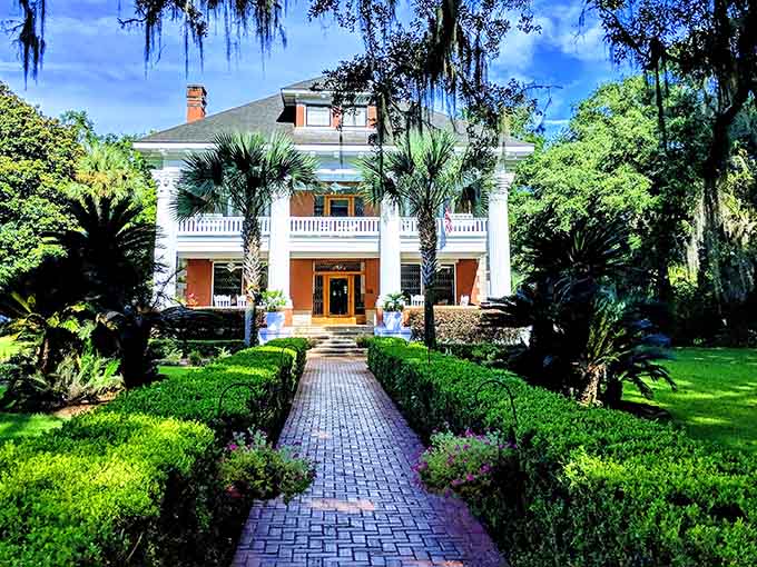 Grand white mansion with manicured gardens and brick walkway that looks like it stepped out of Gone with the Wind.
