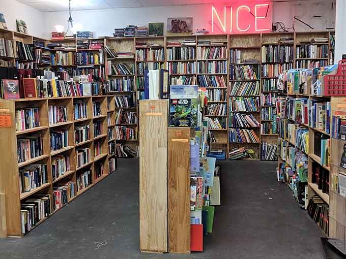 That pink neon "NICE" sign glows above bookshelves packed tighter than a college student's budget.