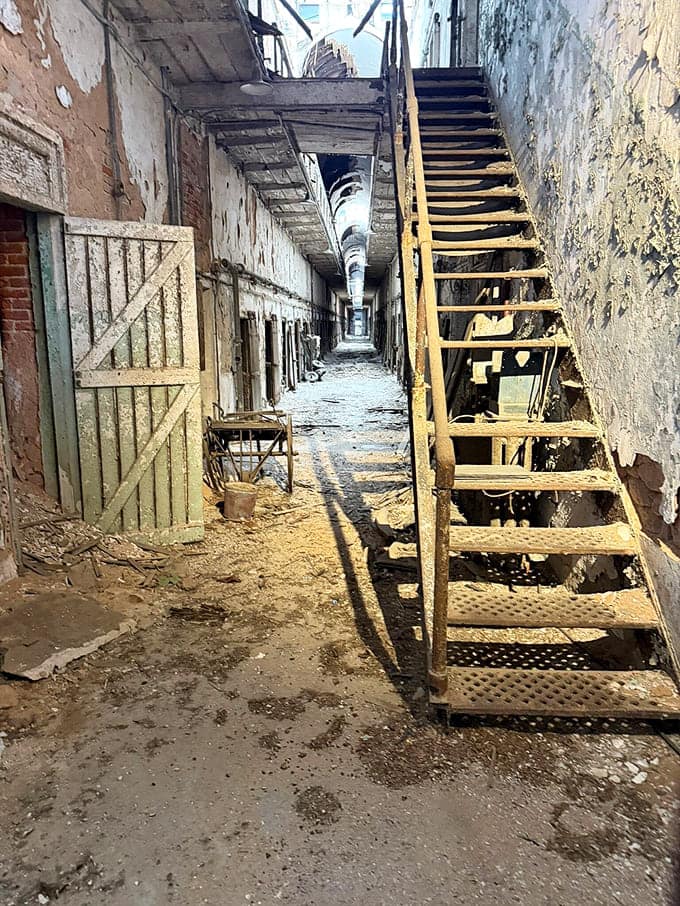 These deteriorating staircases lead to upper tiers where more cells await, each one holding its own untold stories.