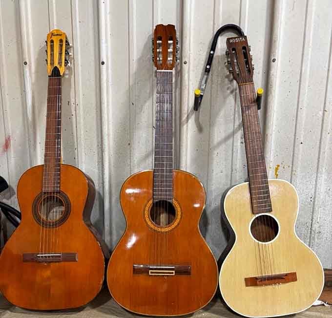 A trio of acoustic guitars waiting for their next serenade. One man's downsized hobby is another's musical beginning.