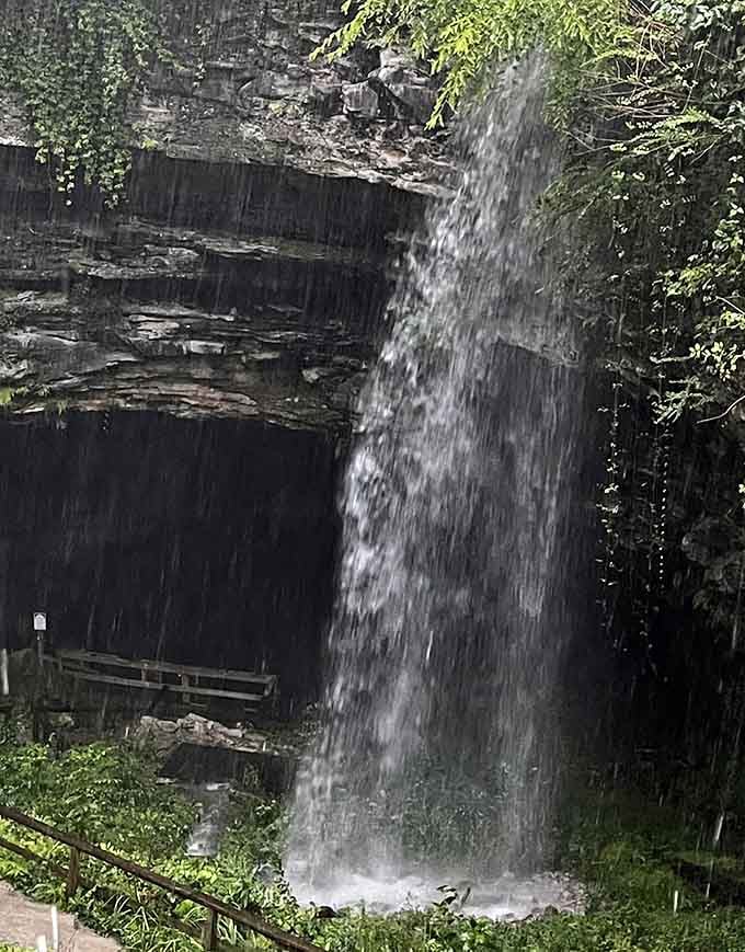A waterfall cascades into the cave entrance, creating a natural curtain between the surface world and underground realm below.