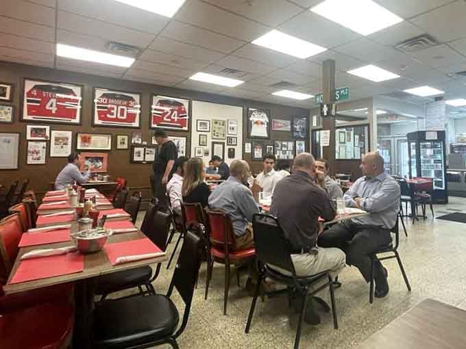 Locals gather around red tables sharing stories and sandwiches, keeping Newark's deli tradition alive and thriving beautifully.