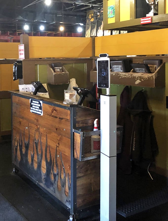 Where barbecue dreams begin. This rustic host station with flame details sets the tone for the smoky experience that awaits beyond its wooden confines.