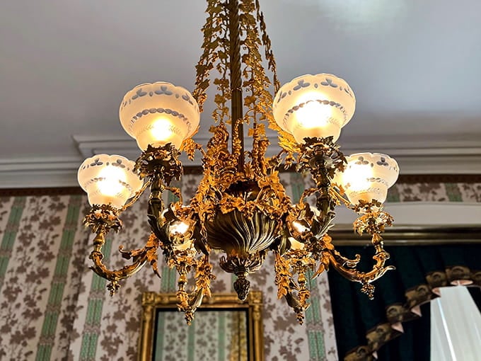 This ornate chandelier drips with golden detail, casting light like jewelry suspended from the ceiling above.