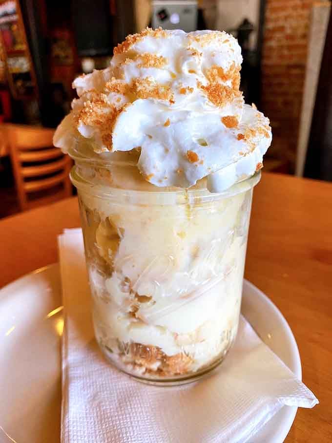 Banana pudding layered high in a mason jar, proving dessert here takes itself seriously too.
