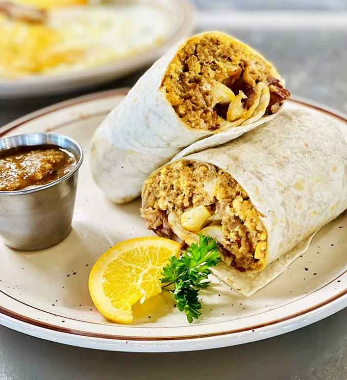 A breakfast burrito stuffed so full it needs structural engineering just to hold together on the plate.