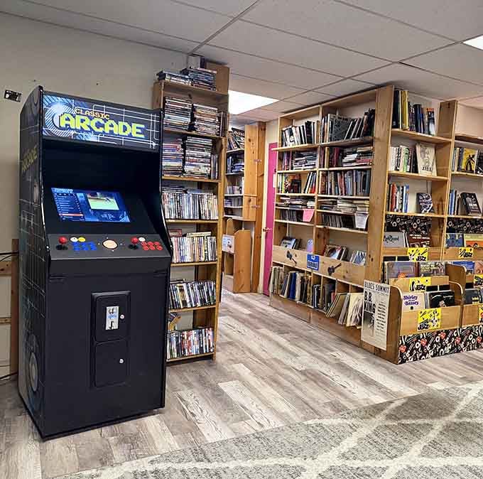 An arcade machine stands ready because apparently someone decided books and vintage gaming make perfect companions, and they were absolutely right.