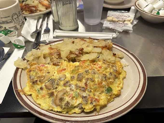 Vegetarian omelette loaded with mushrooms, peppers, and vegetables alongside crispy golden hash browns.