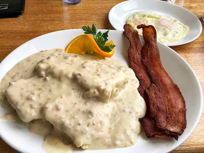 Biscuits buried under sausage gravy in a pink skillet, because presentation matters even when you're being wonderfully indulgent.