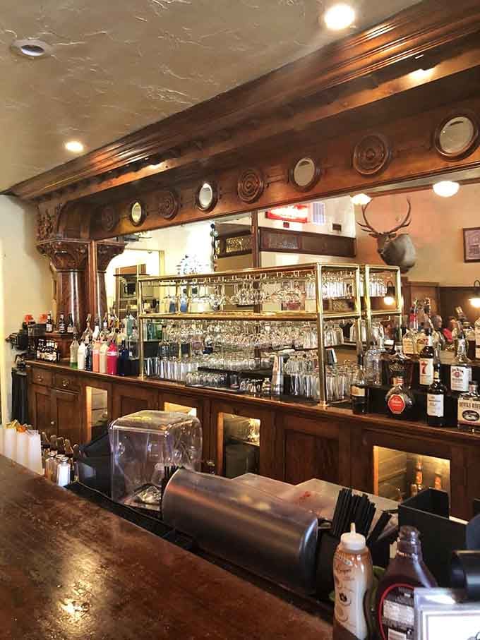 The ornate wooden bar backed by gleaming glassware creates an Old West saloon vibe with modern sophistication mixed in.