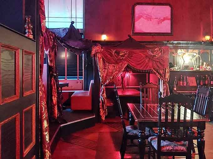 Red velvet draping and intimate seating arrangements that make every meal feel like a secret rendezvous.