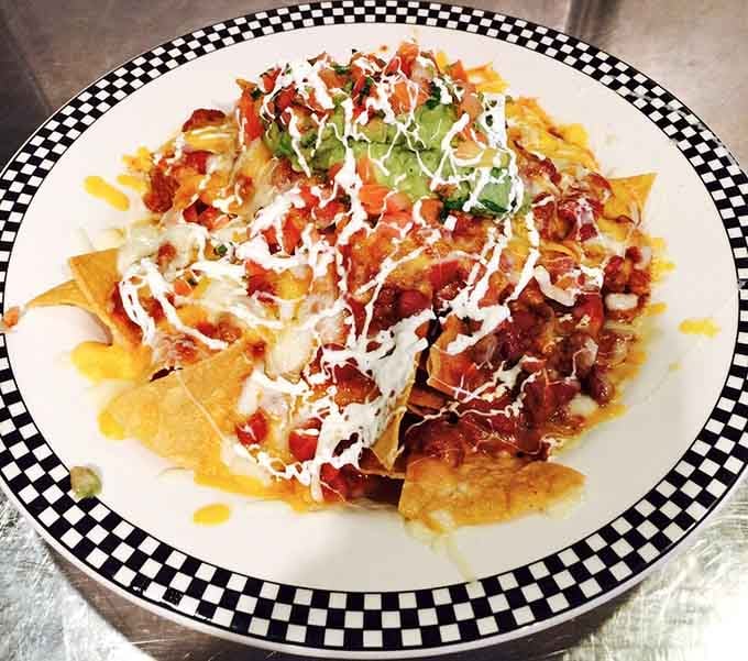 Nachos that require a strategic eating plan—each chip a delivery system for maximum cheese, salsa, and happiness per bite.
