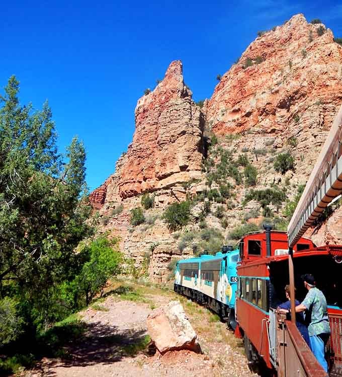 Towering red cliffs dwarf the train below, reminding us that geology always wins the size competition.
