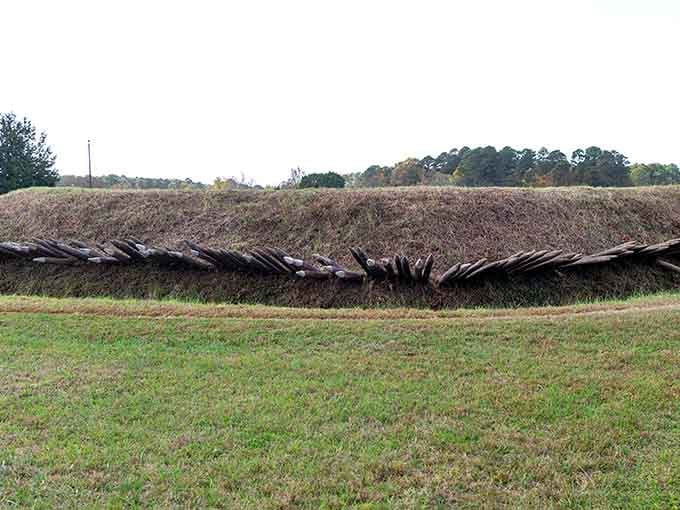 Reconstructed defensive earthworks stretch across the landscape, showing the extensive fortifications that trapped British forces during siege.