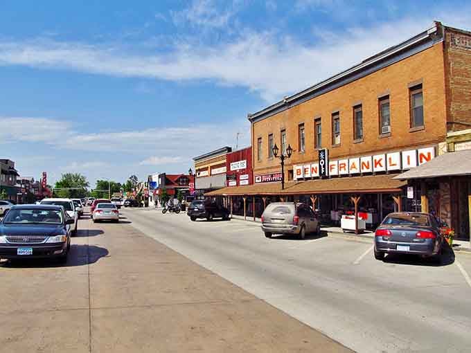 Cars line up along this bustling street where locals and visitors mingle, creating that perfect small-town energy.