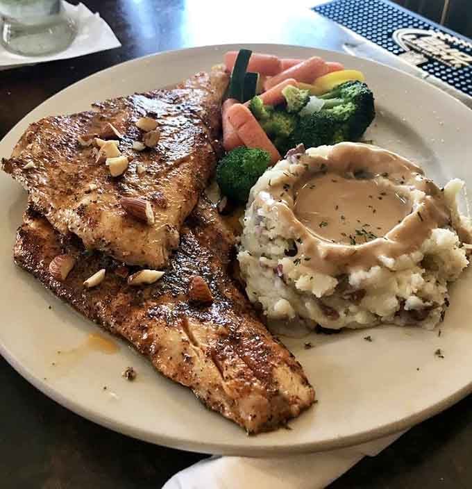 That perfectly cooked whitefish with fluffy mashed potatoes and colorful vegetables is pure Michigan comfort on a single plate.