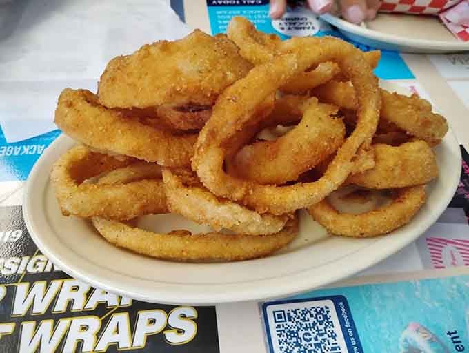 Golden onion rings stacked like edible architecture, crispy enough to hear the crunch from across the table.