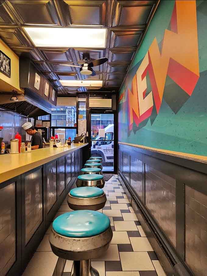 The narrow interior with turquoise stools and colorful wall art creates an unexpectedly cheerful breakfast atmosphere.