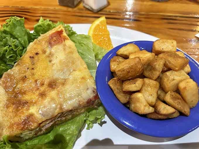 The quiche arrives golden and fluffy, smothered in hollandaise sauce that makes every bite feel absolutely luxurious.