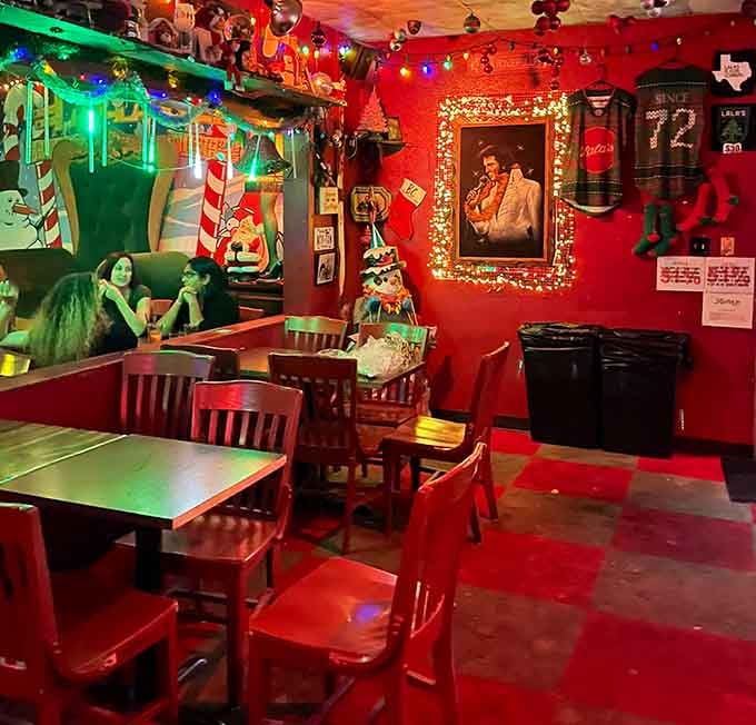 Red walls and Christmas chaos creating the coziest dive bar atmosphere you'll find anywhere.