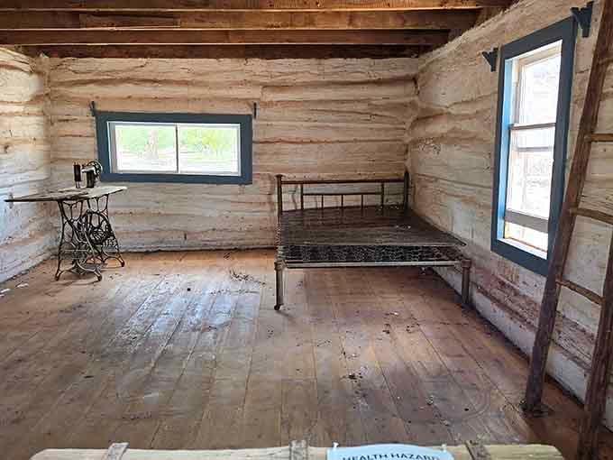 Sparse cabin interior with iron bed frame and antique sewing machine, proving Marie Kondo had nothing on pioneer minimalism.