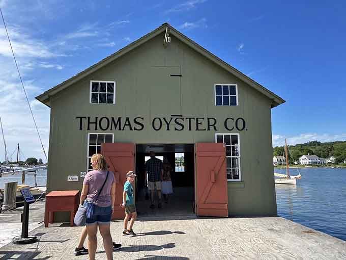 Thomas Oyster Co. building stands waterside in sage green, where maritime commerce once thrived in simpler, saltier times.