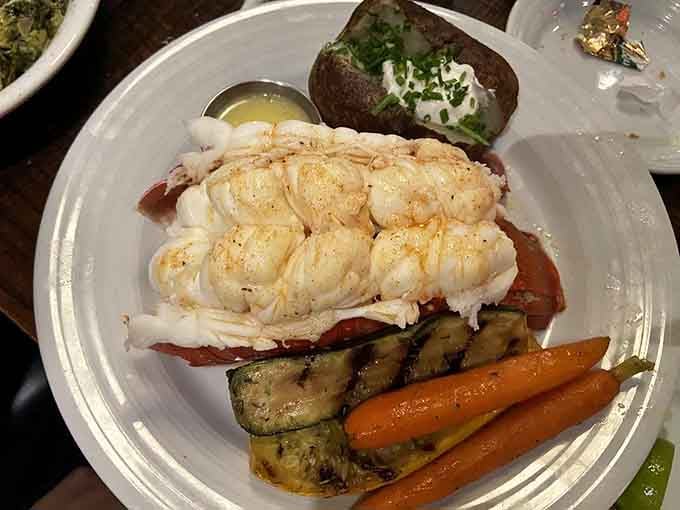 That lobster tail sits majestically on the plate, surrounded by colorful vegetables like royalty holding court over its subjects.