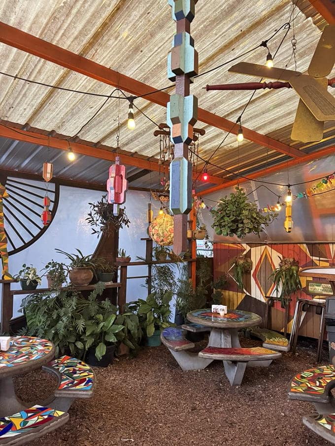 Hanging plants and repurposed bottle lights create a ceiling that's part greenhouse, part artistic statement, all charm.