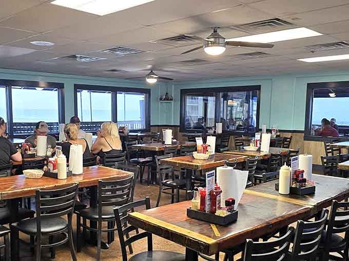 Diners enjoying their meals with floor-to-ceiling windows framing the beach, living their best coastal life one bite at a time.