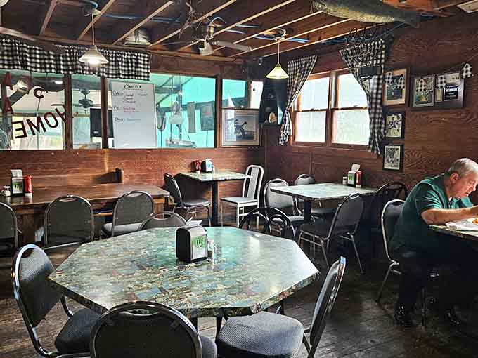 Black and white checkered curtains frame windows in a dining room where comfort matters more than Instagram aesthetics.