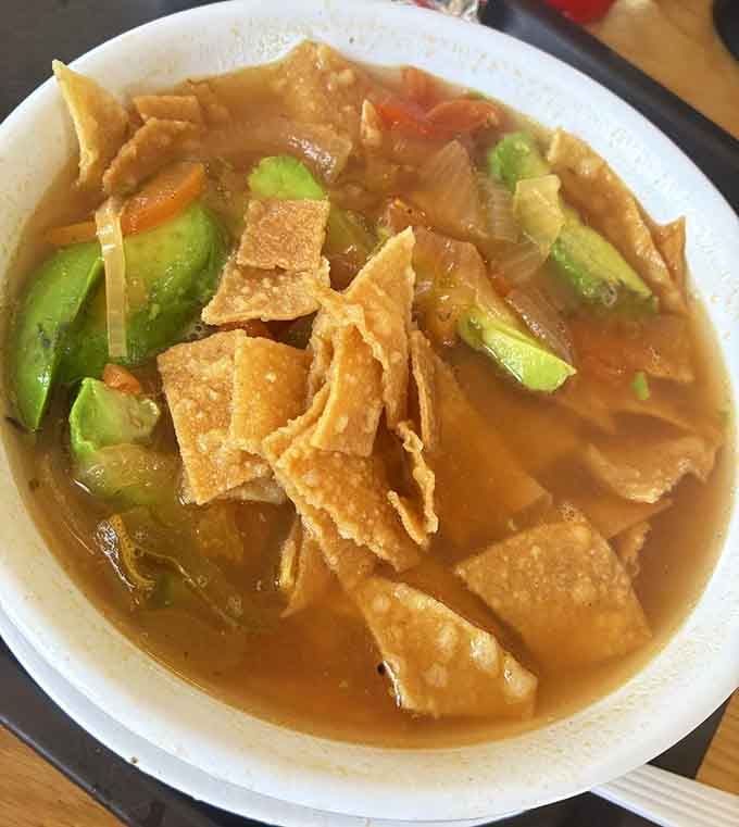 Tortilla soup loaded with avocado and crispy strips proves comfort food transcends all dietary preferences beautifully here.