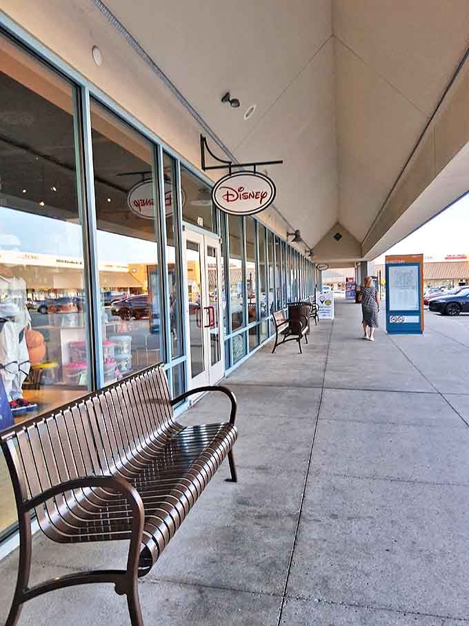 The Disney store entrance stands like a portal to childhood nostalgia. Those benches outside aren't for resting &ndash; they're for partners contemplating their life choices.