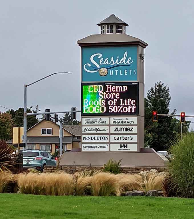 The Seaside Outlets sign stands tall, broadcasting deals like a lighthouse guiding shoppers safely to savings harbor.