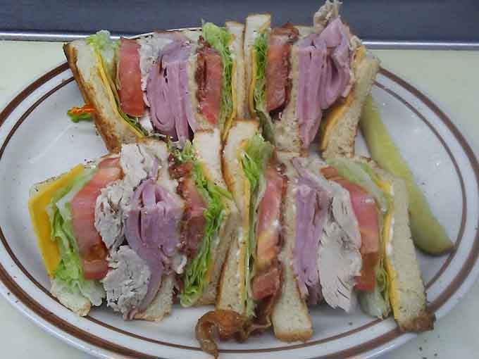 Triple-decker club sandwich stacked high with turkey, ham, bacon, and all the fixings, architectural marvel meets lunchtime perfection.