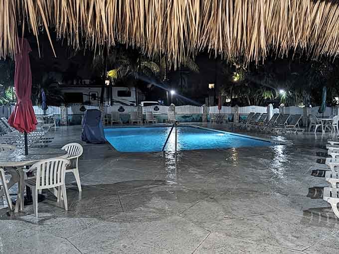 Pool area lit up at night under tiki huts creates that resort vibe without the resort prices.