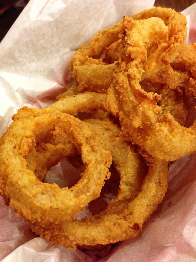 Golden onion rings fried to crispy perfection, because sometimes you need a side that's completely unnecessary but absolutely essential.