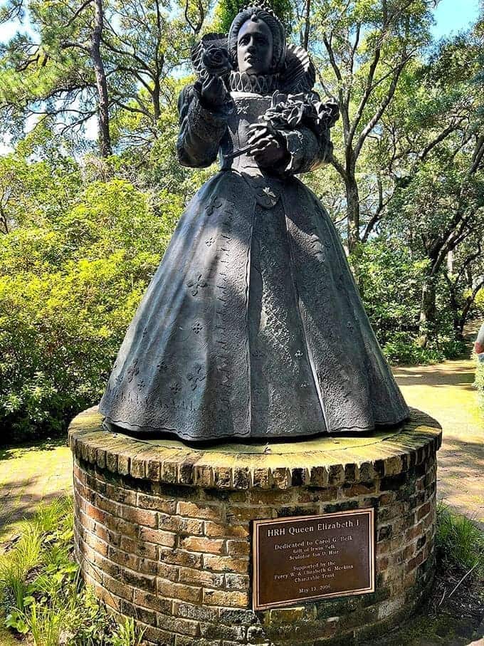 Queen Elizabeth I stands watch over her namesake garden, rose in hand, eternally regal and unbothered.