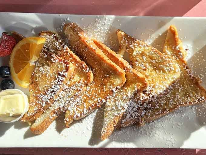 French toast dusted with powdered sugar like edible snow on golden, crispy mountains.