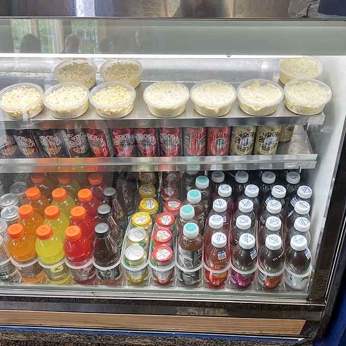 Cold beverages and fresh salads waiting patiently in the cooler, ready to complement your sandwich selection with refreshing precision.