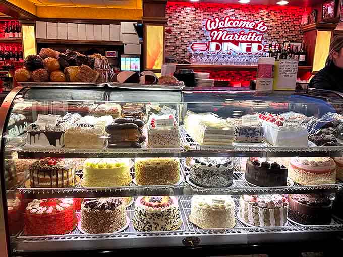 The cake display case is basically a glass monument to temptation, willpower, and inevitable delicious surrender.