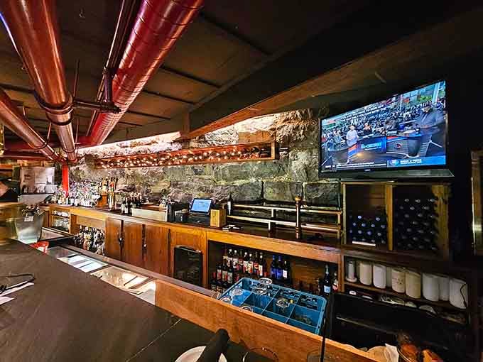 The bar area features exposed stone walls and copper pipes, mixing industrial charm with serious beverage selection expertise.