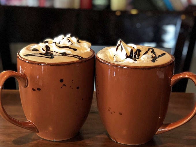 Two mochas with whipped cream mountains and chocolate drizzles. Coffee that doesn't just wake you up&mdash;it gives you a reason to be awake.