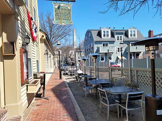 Outdoor seating along a brick sidewalk offers a perfect perch for people-watching in historic Charlestown, with the Bunker Hill Monument visible in the distance.