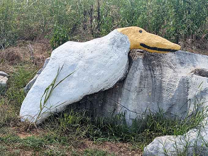 A duck with a yellow bill surveys its rocky domain, forever frozen mid-waddle in this whimsical outdoor gallery.