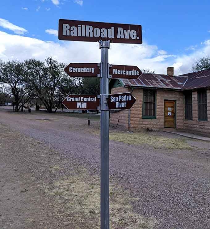 These directional signs help visitors navigate Fairbank's layout, pointing toward the cemetery, mill, and river beyond.