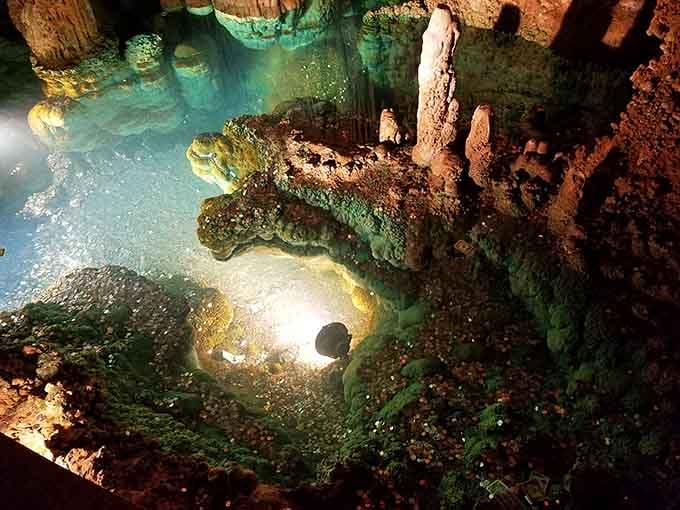 Crystal-clear pools reflect the cavern ceiling, creating mirror images that double the visual spectacle before you.