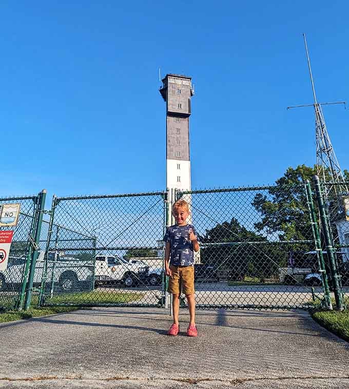A young visitor poses proudly at the gate, dwarfed by the towering triangle that's been photobombing family pictures since the Kennedy administration.